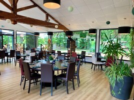 Um restaurante amplo com soalho de madeira, grandes janelas e mobiliário moderno.
