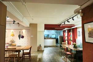 Um interior moderno com mesa e cadeiras de madeira, área de cozinha com bancada e uma parede com detalhes em vermelho.