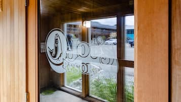 Uma porta de madeira com janela de vidro jateado, um logotipo e vista para o exterior.