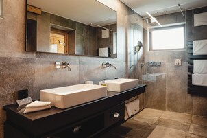 Uma casa de banho moderna com duas pias, um espelho grande e zona de duche.