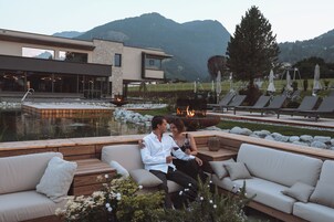 Uma área externa moderna com área de estar, piscina, espreguiçadeiras e deck de madeira.
