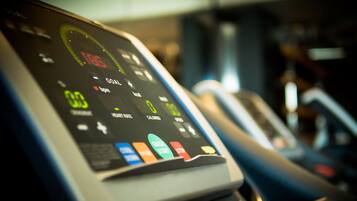 Equipamento de ginástica com visor digital exibindo informações como frequência cardíaca e calorias gastas.