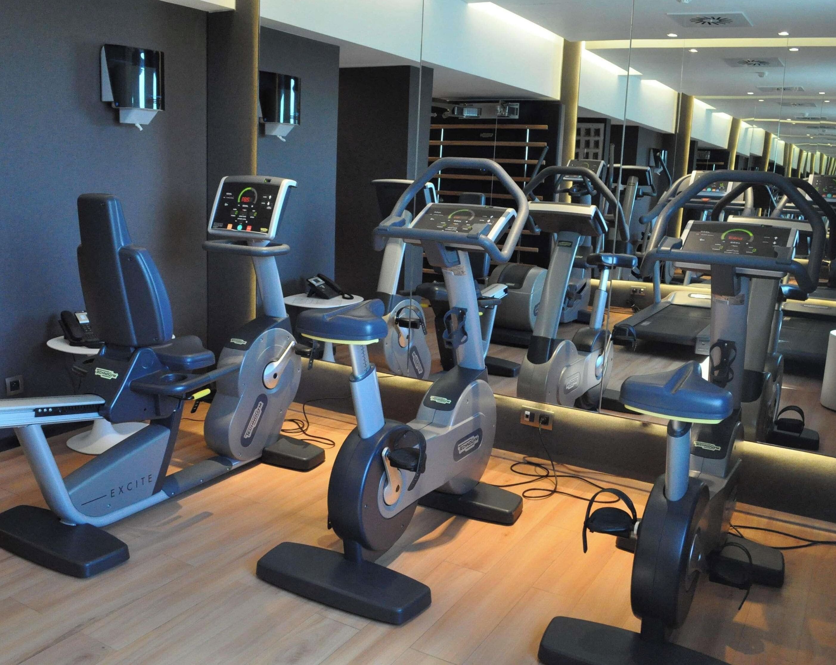 Uma academia com várias máquinas de cardio, incluindo esteiras e elípticos, dispostas em fileiras.
