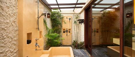 Casa de banho moderna com uma banheira grande, zona de chuveiro e espaço envidraçado com plantas.