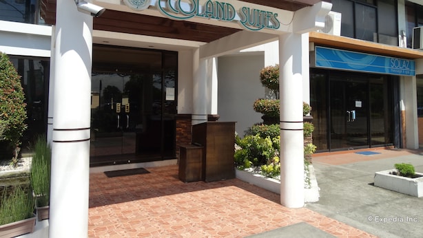 Entrada para ECOLAND SUITES com design moderno, incluindo uma placa, balcão de recepção e plantas em vasos.