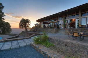 Uma área externa com assentos, degraus de pedra e mesas, com vista para uma paisagem deslumbrante.