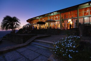 Um edifício com terraço, mesas ao ar livre e vista para o mar.