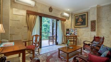 Uma sala de estar espaçosa com uma mesa de centro de madeira, poltronas estofadas em vermelho e uma grande janela com cortinas.