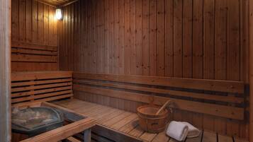 Uma sauna de madeira com bancos, uma banheira de hidromassagem e um balde de madeira com concha.