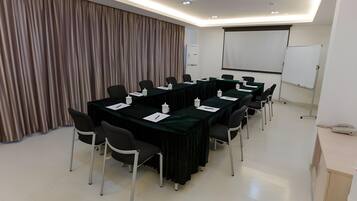 Uma sala de conferências com uma mesa comprida, cadeiras, um projetor e uma lousa.