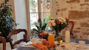Uma mesa de café da manhã com croissants, pão, doces e uma cesta de frutas.