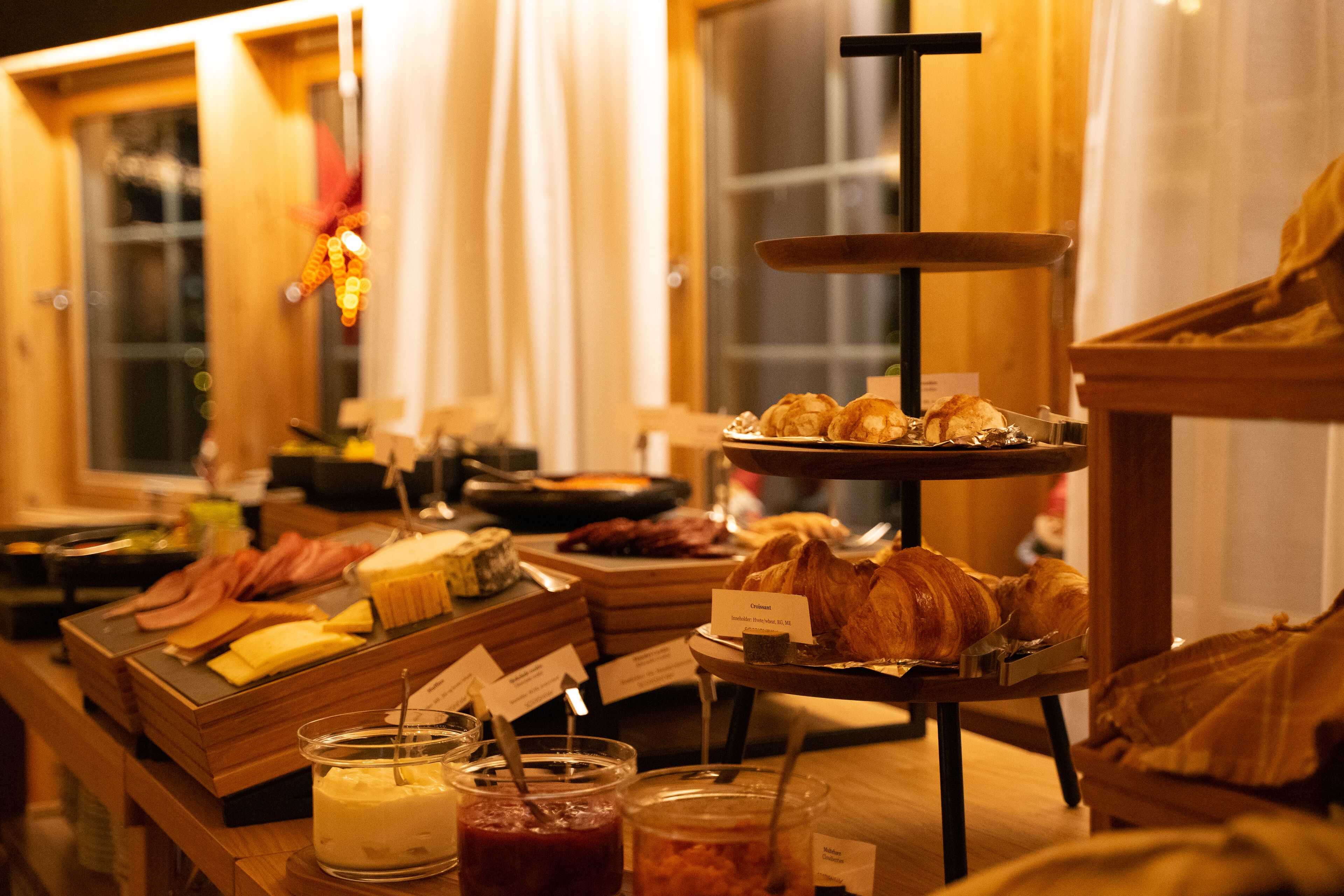 Buffet com diversos alimentos e bebidas, incluindo pastelaria, queijos e uma seleção de sumos.