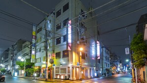 Um edifício de vários andares com espaço comercial no térreo, várias placas e uma rua com bicicletas estacionadas.