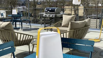 Pátio externo com mobiliário azul e amarelo, incluindo cadeiras e mesas.