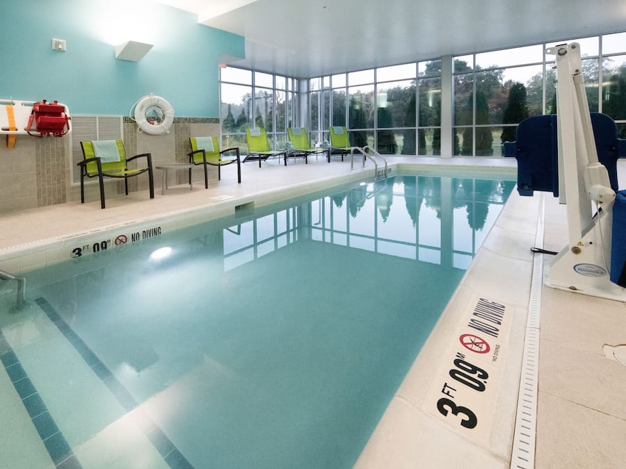 Piscina interior com água cristalina, marcações de profundidade e posto de salva-vidas.
