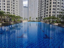 Piscina rodeada por edifícios altos, com céu claro acima.