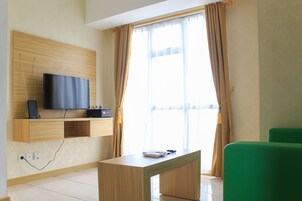 Uma sala de estar moderna com uma TV de tela plana fixada em uma parede de madeira, um sofá verde e uma pequena mesa de centro.