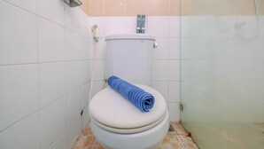 Casa de banho com toalha azul no assento, área de duche e paredes em azulejo.