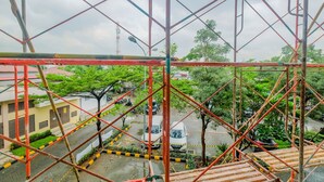 Vista de um ponto elevado, provavelmente uma varanda ou terraço, com vista para um estacionamento com vários carros e vegetação exuberante.
