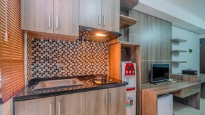 Uma cozinha moderna com armários de madeira, painel de fundo xadrez, micro-ondas embutido e uma geladeira compacta.