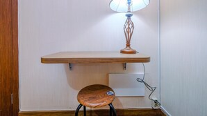 Mesa de canto com luminária, cadeira e tomada.