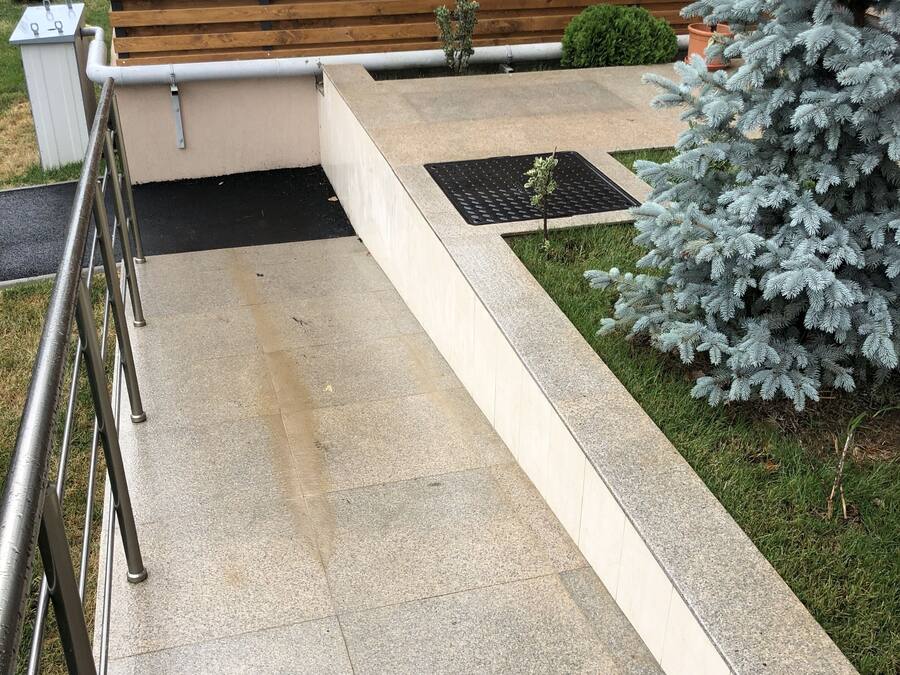 Uma passarela de concreto leva a um banco de madeira com um guarda-corpo de metal.