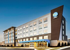 Um edifício de hotel moderno com uma placa 'tru' chamativa, vários andares e uma entrada bem iluminada.