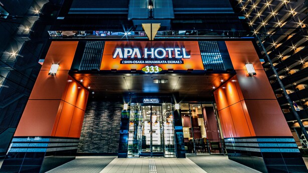 Entrada do APA HOTEL com design moderno, destacando uma placa e fachada de vidro.