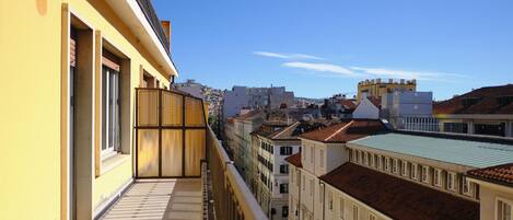 Uma varanda com vista para uma paisagem urbana, com edifícios de diversos estilos arquitetônicos.