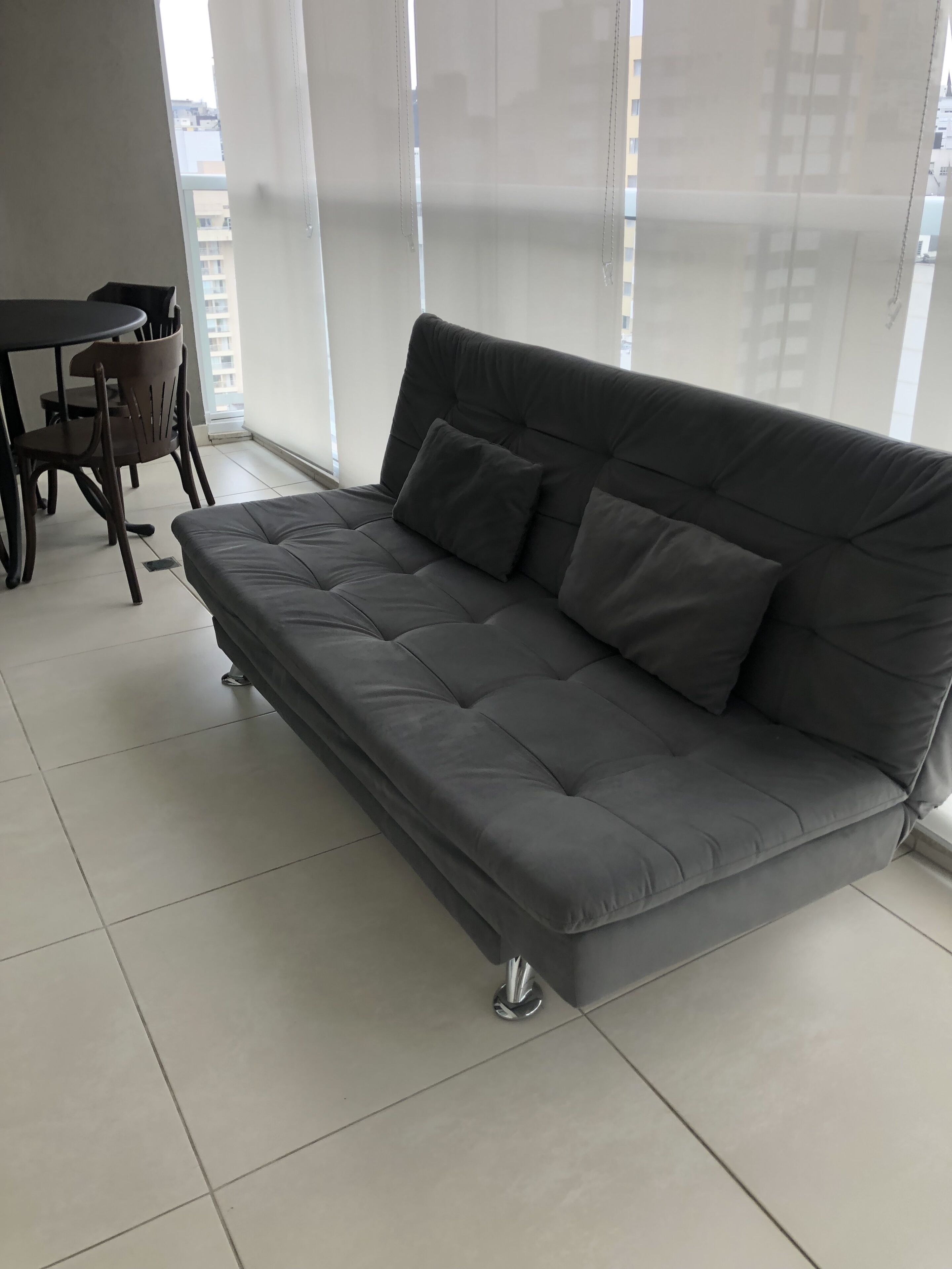 Uma sala de estar moderna com um sofá cinzento, uma mesa de jantar de madeira e cadeiras.