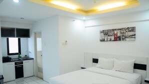 Quarto de hotel com cama, pequeno kitchenette e obra de arte na parede retratando pontos turísticos.