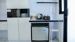 Uma cozinha compacta equipada com geladeira, pequena geladeira, cafeteira, chaleira e máquina de café para viagem.