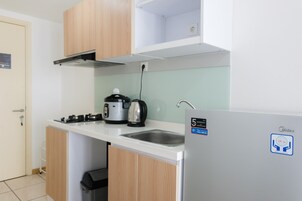 Uma cozinha compacta com fogão a gás embutido, cafeteira e pia de aço inoxidável.