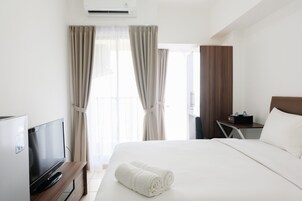 Quarto de hotel com cama, televisão, escrivaninha e cortinas.