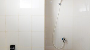 Casa de banho com paredes revestidas de azulejos brancos e zona de duche com chuveiro manual.