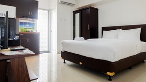 Quarto de hotel com cama, escrivaninha, computador, guarda-roupa e ar condicionado.