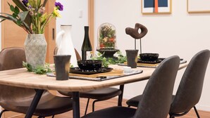 Uma mesa de jantar com pratos pretos, um vaso com flores e uma cúpula de vidro decorativa.