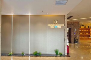 Um hall de hotel moderno com uma recepção, uma parede de mármore e interior bem iluminado.