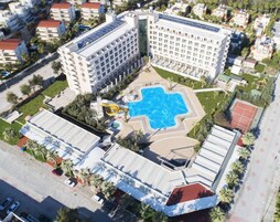 Vista aérea de um hotel com piscina, quadra de tênis e área de recreação infantil.