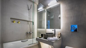 Casa de banho moderna com banheira, cabine de duche envidraçada, espelho grande e sanita.