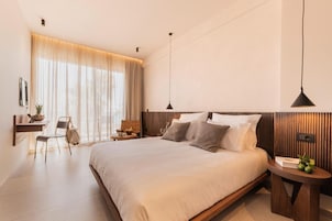 Um quarto moderno com uma cama grande, mesas de cabeceira, uma escrivaninha e uma cadeira.