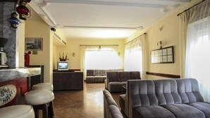 Uma sala de estar com sofá, televisão e área de bar com banquetas.