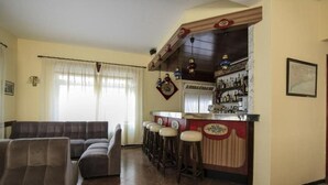 Uma sala de estar com área de bar, incluindo sofás e banquetas.