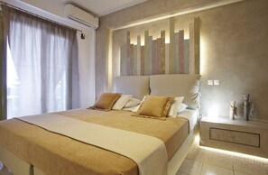 Quarto com cama grande, mesa de cabeceira e luminária na parede.