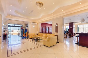 Um hall amplo com um sofá grande, um balcão de recepção e um candelabro.