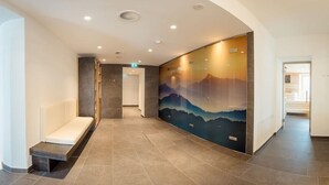 Um corredor moderno com um banco, um mural e uma escadaria.