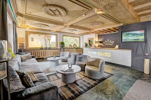 Um saguão de hotel moderno com balcão de recepção, área de estar e grandes janelas.