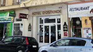 Um hotel com fachada clássica, várias janelas com persianas e uma placa indicando que é um hotel.