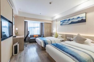 Quarto de hotel com duas camas, uma escrivaninha, uma cadeira, uma televisão e um quadro na parede.