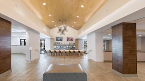 Um hall espaçoso com teto alto, área de bar central e espaço para sentar com um banco.